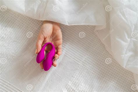 A Faceless Woman Lies In Bed Under A Blanket Holding A Clitoral Vaginal
