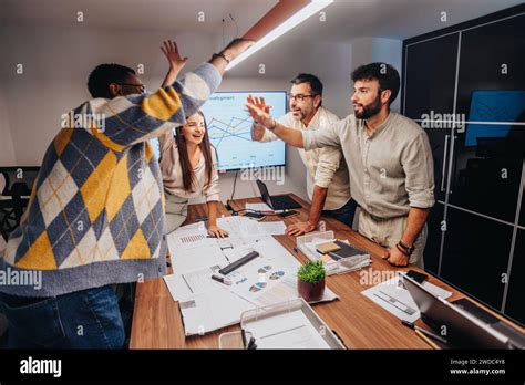 Multinational Team Collaborates In A Board Room Discussing Architectural Blueprints And