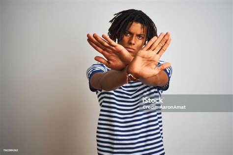 고립 된 흰색 배경 위에 서있는 줄무늬 파란색 폴로를 입은 공포를 가진 아프로 남자 팔과 손바닥을 교차하는 부정적인 기호 화가 얼굴 개념에 대한 스톡 사진 및 기타 이미지