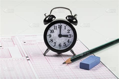 高中生或大学生手拿试卷，在答题纸上写试卷，标准化考试光学形式放在桌上，在教室里做期末考试。教育素养的