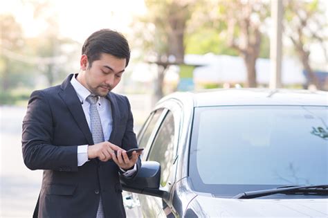 นักธุรกิจรูปหล่อใช้โทรศัพท์มือถือเลิร์นบนรถของเขา ภาพสต็อก ดาวน์โหลดรูปภาพตอนนี้ รถยนต์