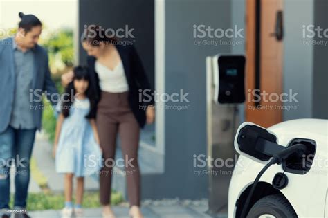 Ev 자동차용 가정용 충전소에 초점을 맞추고 배경에서 진보적인 가족을 흐리게 합니다 3 명에 대한 스톡 사진 및 기타 이미지 3 명 가리키기 가족 Istock