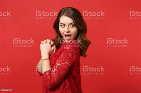 의 측면 보기 흥분 깜짝 젊은 여자 레이스 드레스를 유지 입 오픈 옆에 고립 된 밝은 빨간색 벽 배경에 스튜디오 사람들은 진심으로 감정 라이프 스타일 개념입니다 복사 공간을