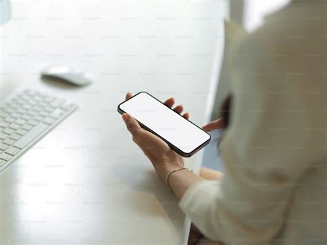 컴퓨터 책상에 모형 화면이 있는 스마트폰을 들고 있는 여성의 자른 사진 클리핑 경로 사진 Unsplash의 사진술 이미지