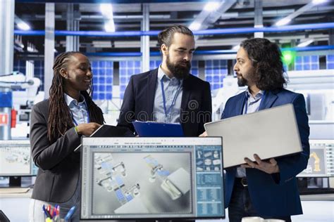 Engineering Team In Solar Panel Plant Adjusting Robotic Machinery