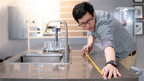 젊은 아시아 남자 쇼 룸에서 현대 부엌 카운터에 화강암 싱크대를 측정 하기 위한 측정 테이프를 사용 하 여 홈 개선 위한 가구 쇼핑 인테리어 디자인 컨셉 인테리어 디자이너에
