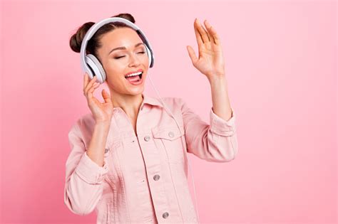 그녀의 클로즈업 초상화 그녀의 멋진 찾고 매력적인 쾌활한 쾌활한 꿈꾸는 소녀는 핑크 파스텔 배경을 통해 고립 된 새로운 트랙 리스트 Mp3 오디오 플레이어를 즐기고 가수에