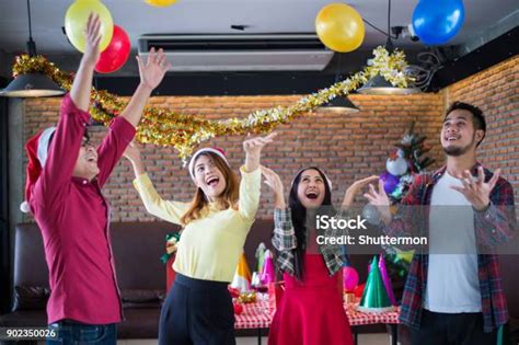 아시아 남자와 여 자가 크리스마스 파티에서 재미 춤 및 레스토랑 개념의 크리스마스 파티 또는 새 해 파티에서 풍선 게임 산타 클로스 모자를 착용 가족에 대한 스톡 사진 및