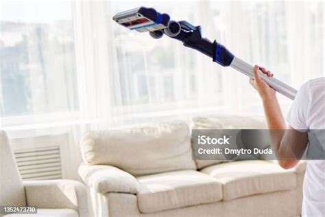 집에서 거실 백 뷰 복사 공간에서 청소하는 동안 손 무선 진공 청소기에 들고 흰색 셔츠에 젊은 여성의 가까이 집안일 청소 및