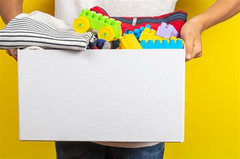 기부 개념입니다 책 옷 장난감 Ober 노란색 배경기부 상자를 들고 아이 손 Charitable Foundation에 대한 스톡