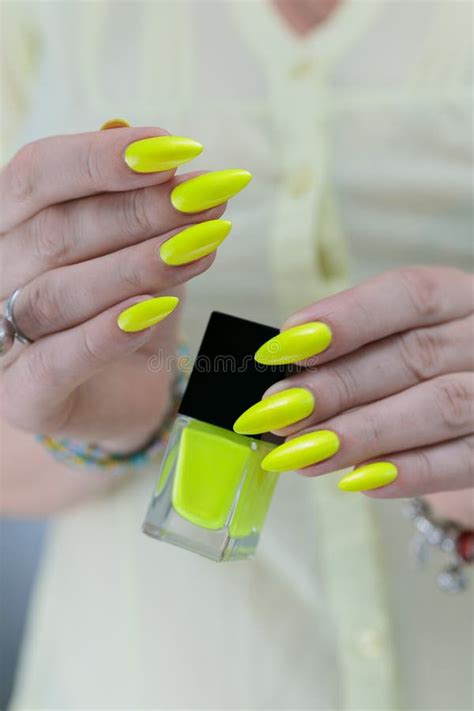 Female Hand With Long Nails And Bright Yellow Green Neon Nail Polish