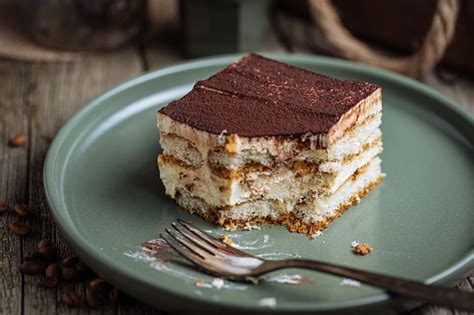 전통적인 이탈리아 디저트 인 티라미수 케이크 한 조각이 변덕스럽고 소박한 장면에서 제공됩니다 나무 배경과 녹색 접시 0명에 대한 스톡 사진 및 기타 이미지 Istock