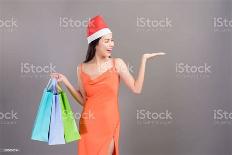 빨간 산타 클로스 모자를 쓰고 젊은 미소 여자의 초상화는 신용 카드와 화려한 쇼핑 백을 들고 회색 배경 스튜디오 크리스마스와 새해 개념 가방에 대한 스톡 사진 및 기타