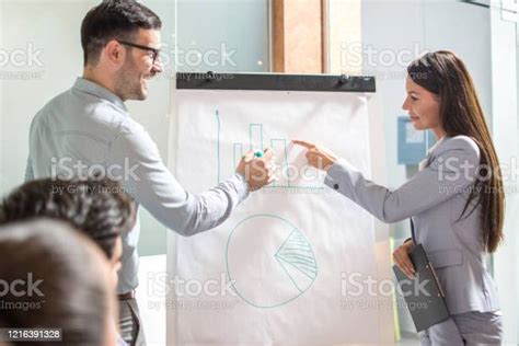 회의실에서 비즈니스 미팅을 하는 동안 플립차트에 그래프를 스탠딩하고 제시하는 사업가 모임에 대한 스톡 사진 및 기타 이미지