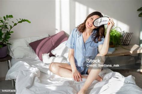 행복한 아침 잠옷을 입은 아름다운 갈색 머리 여성이 침실에 있는 침대에 앉아 있다 행복한 여자가 새로운 날을 맞이한다 침실 인테리어 컨셉입니다 화창한 아침 30 39세에