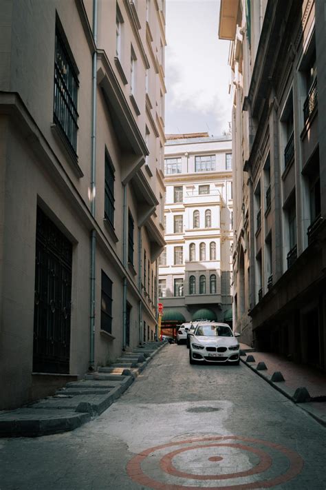 주차된 차와 건축물이 있는 도시 골목길 · 무료 스톡 사진