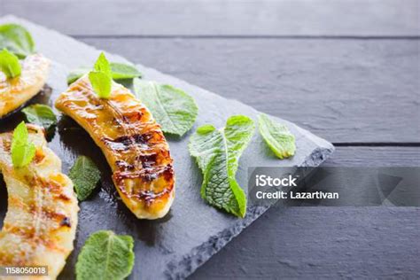 검은 부엌 보드와 셰일 스톤에 구운 바나나의 절반 검은 배경에 민트와 구운 바나나 디저트 아시아 건강 식품 도마 요리 도구에 대한 스톡 사진 및 기타 이미지 Istock