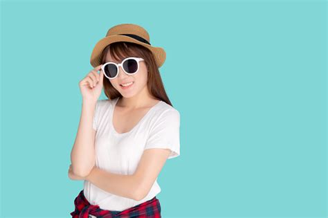 아름다운 초상화 젊은 아시아 여성은 모자를 착용하고 파란색 배경에 고립 된 휴가 여름 여행을 즐길 자신감 선글라스를 들고 여행과 관광 아시아 소녀 명랑 관광객에 대한 스톡