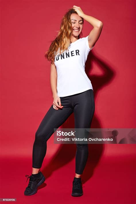 스포티 한 바디는 빨간색 바탕에 스튜디오에서 포즈 젊은 해피 피트 니스 소녀 아름 다운 맞는 소녀 화이트 러너에서 피트 니스 모델 T셔츠 체중 감량입니다 건강 한 생활