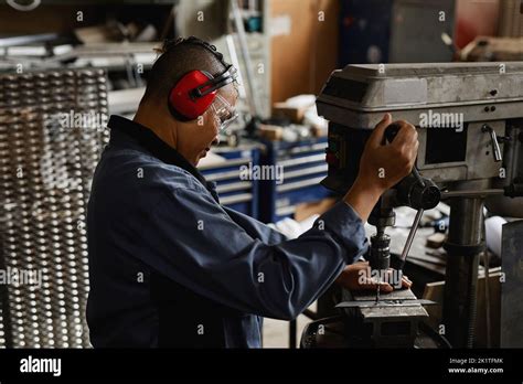 Back View Of Female Worker Operating Machine Units In Industrial Workshop And Wearing Protective
