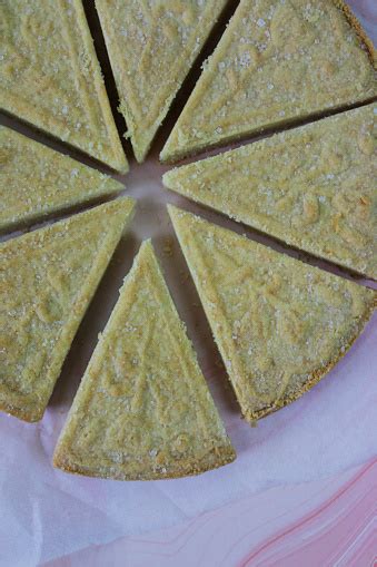 엉겅퀴 금형 패턴 디테일을 보여주는 슬라이스 버터 수제 쇼트 브레드 라운드의 이미지 오븐에서 신선한 황금 갈색 삼각형으로 잘라 핑크 대리석 효과 배경 전경에 초점 0명에