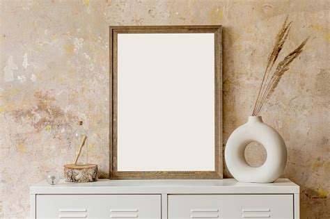 흰색 Commode에 갈색 나무 모형 포스터 프레임 꽃과 우아한 개인 액세서리 디자인 꽃병과 거실의 세련된 구성 현대 그런 지