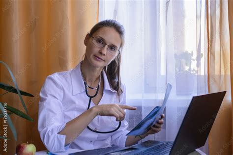 врач внимательно изучает рентгеновский снимок в кабинете поликлиники ...