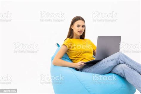 젊은 여성은 신생 고객과 그녀의 컴퓨터 채팅에서 작업 큰 가방 라운지 의자는 흰색 색상 배경에 고립 된 캐주얼 스타일의 옷을