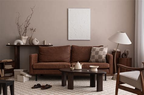 모형 포스터 프레임 갈색 소파 세련된 램프 체스 프린트 카펫 커피 테이블 부클 안락의자 및 개인 액세서리가 있는 아늑한 거실 인테리어의 창의적인 구성 가정 장식 템플렛 0