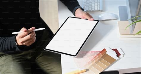 젊은 남성 그래픽 디자이너의 자른 샷은 워크 스테이션에서 대화 형 펜과 빈 화면 디지털 태블릿으로 작업하고 있습니다 사진 Unsplash의 조직 이미지