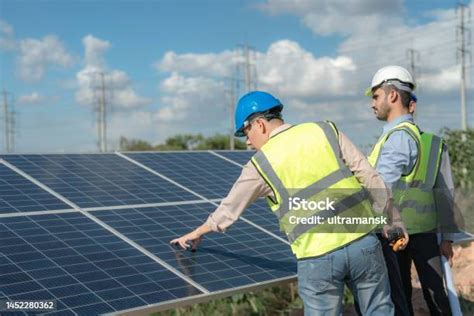 엔지니어 는 전자 장치로 태양 전지 패널 또는 태양광 전지의 건설을 검사합니다 녹색 전력의 산업 재생 에너지 타워 지붕에서 일하는 공장 노동자 2명에 대한 스톡 사진 및