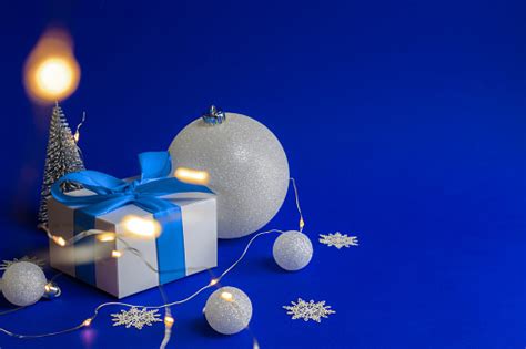 크리스마스 장식품 파란색 리본 겨울 나무 눈송이 실버 볼이 있는 흰색 선물 상자가 파란색 배경에 있는 크리스타 장식으로 인사말