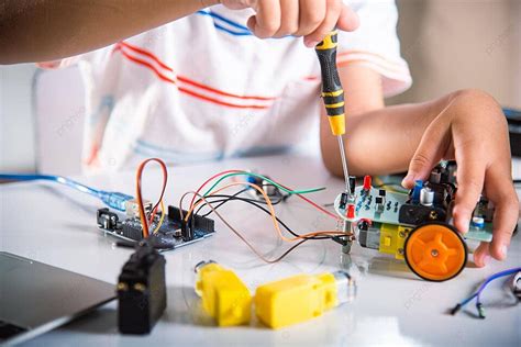 Boy Of Asian Descent Constructing An Arduino Robot Car For A Homework