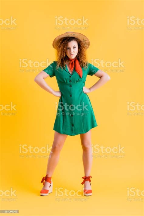 밀짚 모자와 노란색에 엉덩이에 손으로 서 녹색 드레스에 불쾌한 여자의 전체 길이 전신에 대한 스톡 사진 및 기타 이미지 전신