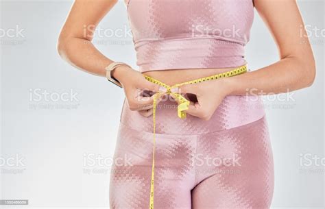 여자 손 줄자는 회색 스튜디오 배경에 대해 체중 다이어트 또는 피트니스를 줄입니다 운동 운동 또는 스포츠 후에 건강한 몸을 위해서 허리의 측정을 하는 여성의 손 여자에 대한