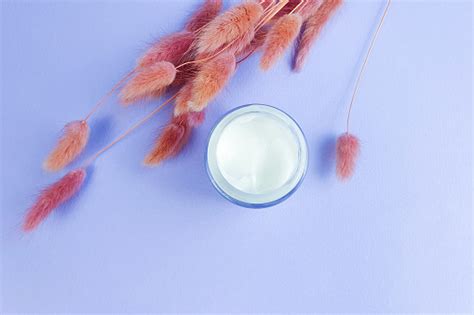 화이트 모이스처라이저 페이셜 또는 아이 크림은 오픈 글래스 항아리에 질감이 있는 보라색 배경의 핑크 라구루 복사 공간이 있는 상단 뷰입니다 0명에 대한 스톡 사진 및 기타