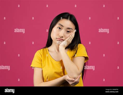 Bored Young Chinese Lady Feeling Upset And Depressed Looking At Camera Posing Over Pink
