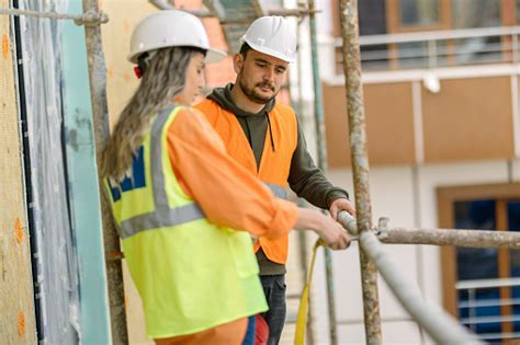 건설 현장 작업자에게 안전 하네스 사용 방법을 설명하는 여성 산업 안전 전문가 건설 현장에 대한 스톡 사진 및 기타 이미지 건설 현장 건설 산업 안전 Istock