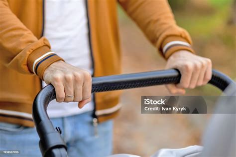 공원을 걷는 동안 유모차에 손을 얹은 남자의 근접 촬영 부모의 개념 에코 가죽으로 만든 방수 및 방풍 신생아 캐리지 아기 수송 가을에 대한 스톡 사진 및 기타 이미지