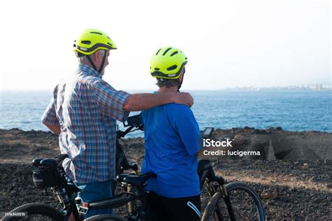 해질녘에 바다를 바라보는 노인 부부의 뒷모습은 자전거로 자전거를 타게 됩니다 건강한 라이프 스타일과 즐거움 감정에 대한 스톡