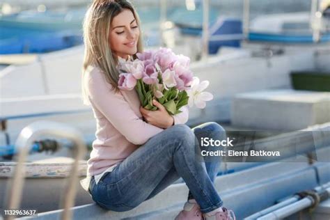 봄 또는가을 보트 베이에 있는 바다로 아름 다운 소녀 그의 손에 꽃의 꽃다발과 꽉 세련 된 청바지와 핑크 스웨터 갈색에 대한 스톡 사진 및 기타 이미지 Istock