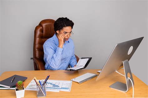 안경을 쓴 젊은 사업가가 사무실의 책상에서 문서와 컴퓨터를 들고 작업에 집중하고 있습니다 25 29세에 대한 스톡 사진 및 기타 이미지 25 29세 검정 머리 결심