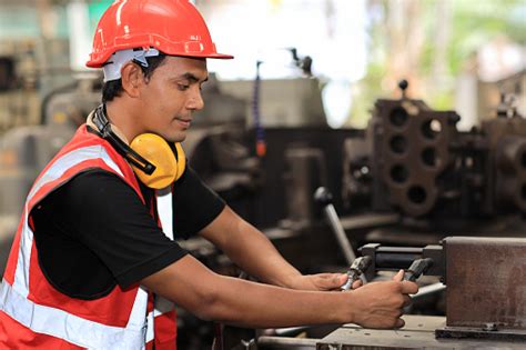 중공업 제조 공장에서 안전모로 작업을 제어하거나 산업 기계 프로세스를 확인하는 동안 보호 유니폼을 입고 컴퓨터를 사용하는 기술자