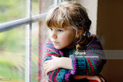 창가에 앉아 있는 어린 소녀 유치원 어린이는 아늑한 니트 울 스웨터를 착용합니다 밖에서 비를 보고 있는 유아 가을과 겨울 시즌 가정 생활에 대한 스톡 사진 및 기타 이미지
