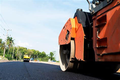무거운 진동 롤러 압축기아스팔트 도로 롤러는 도로 건설 현장의 도로에 새로운 뜨거운 아스팔트를 누릅니다 아스팔트 포장 작업에서 무거운 진동 롤러 복구 0명에 대한 스톡 사진