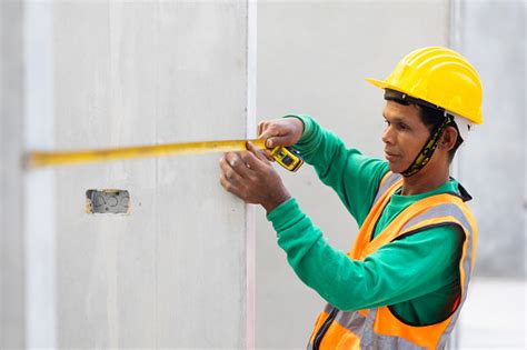 측정 테이프를 사용하고 프리캐스트 콘크리트 벽 공장에서 일하는 고위 아시아 남성 노동자 노란색 줄자 건설 도구 중공업 제조 공장