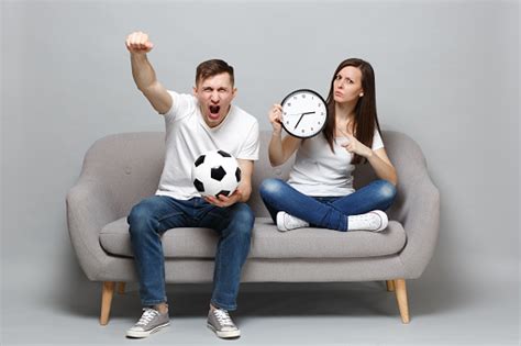 커플 여자 남자 축구 팬을 비명을 지 원하는 축구 공을 좋아하는 팀을 응원 라운드 시계를 들고 회색 벽 배경에 고립 된 주먹을