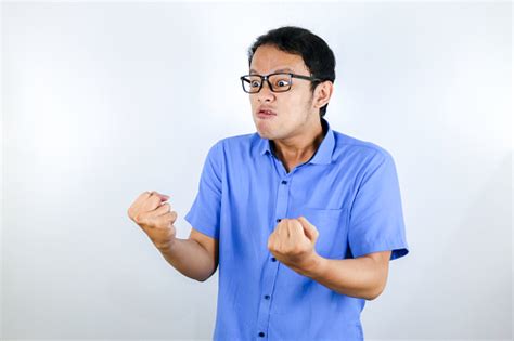 젊은 아시아 남자 입고 파란색 셔츠는 흰색 배경 위에 고립 된 카메라에서 소리지르고 손가락을 가리키는 재미있는 화가 얼굴입니다 20 29세에 대한 스톡 사진 및 기타 이미지