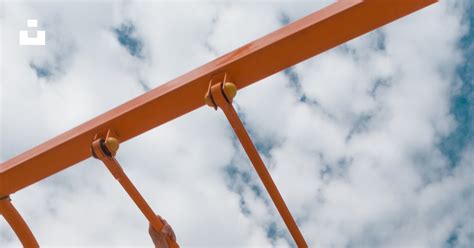 검은 셔츠와 파란색 데님 청바지를 입은 소녀는 파란색과 흰색 아래에서 주황색 스윙을 타고 있습니다 사진 Unsplash의