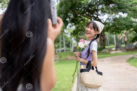 Lovely Smiling Asian Girl Is Having Her Photo Taken By A Friend While